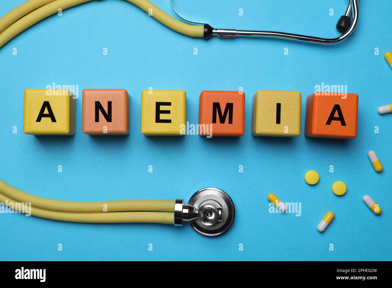 Word Anemia made with wooden cubes, pills and stethoscope on light blue ...
