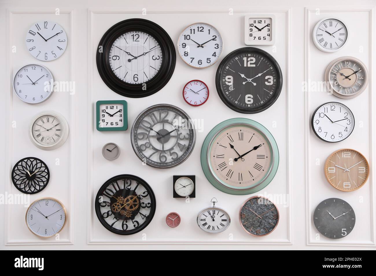 Collection of different clocks hanging on white wall Stock Photo - Alamy