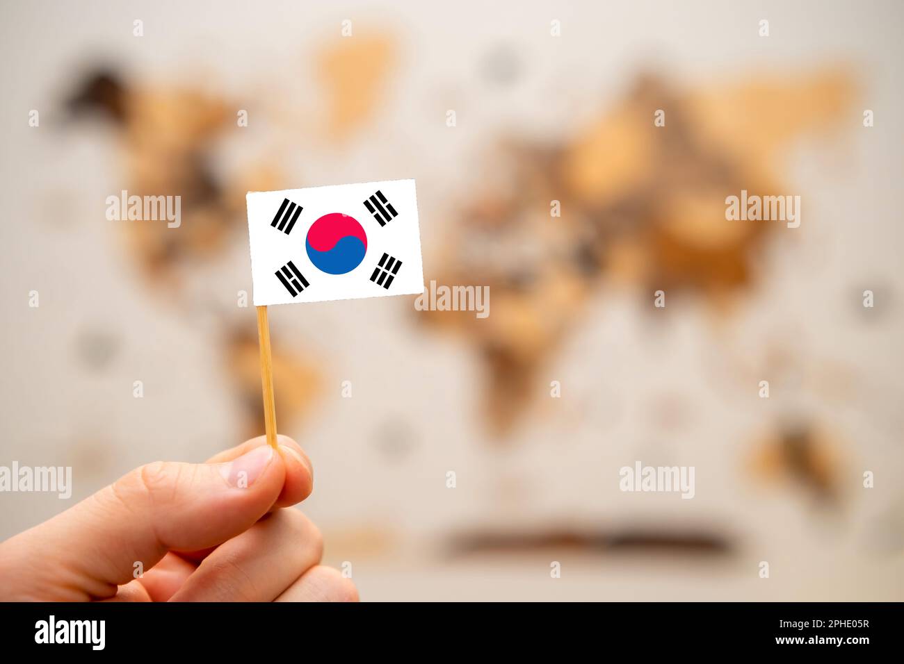 South Korean flag in mans hand on the wooden world map background ...