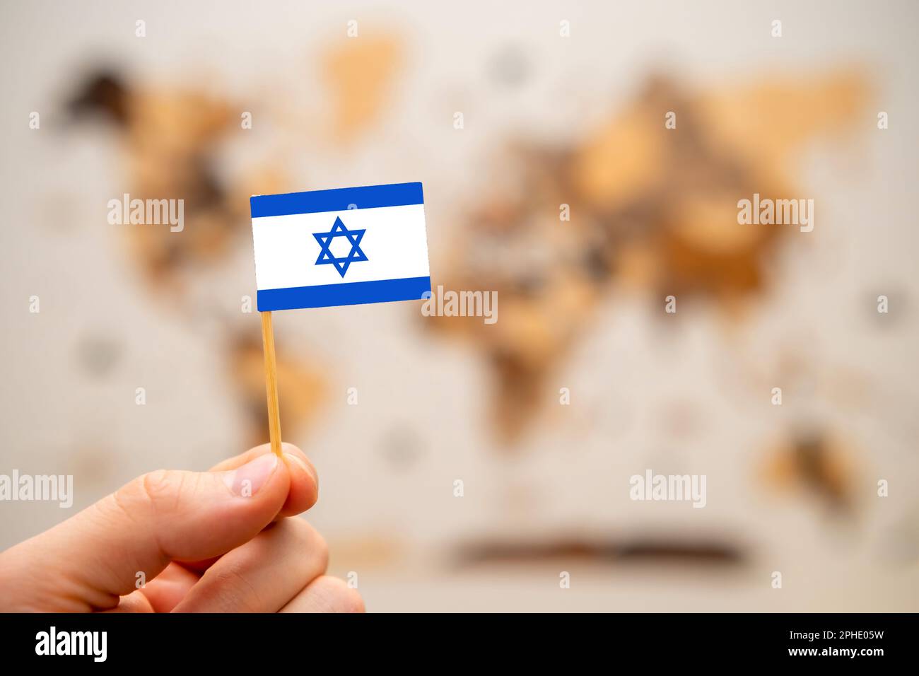 Israel flag in mans hand on the wooden world map background. Global ...