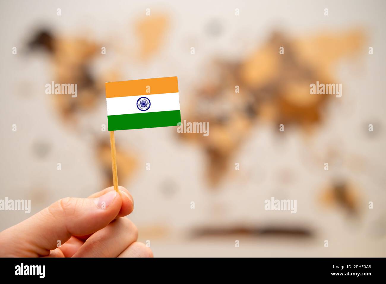 India flag in mans hand on the wooden world map background. Global ...