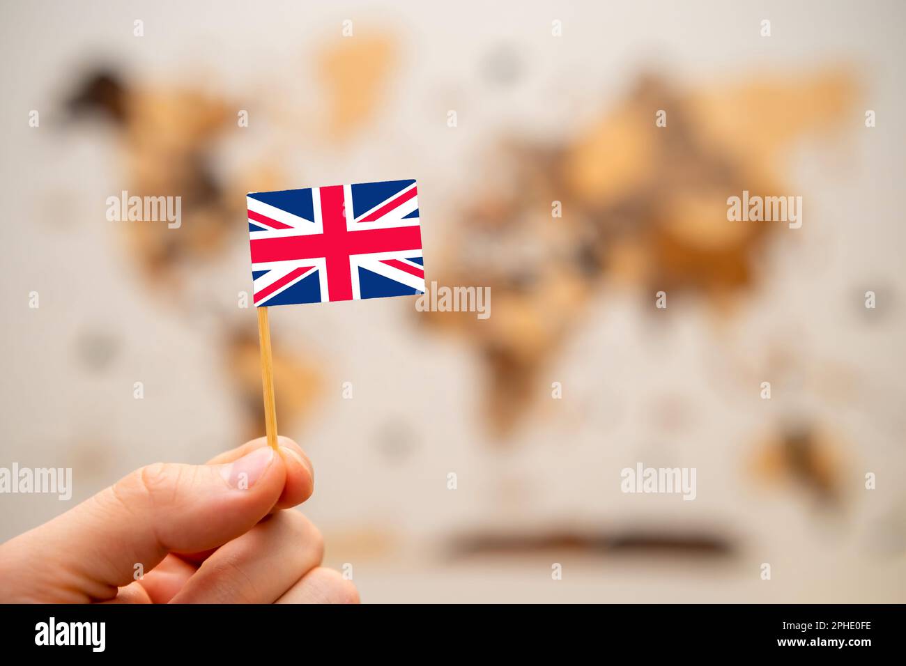 British flag in mans hand on the wooden world map background. Global ...