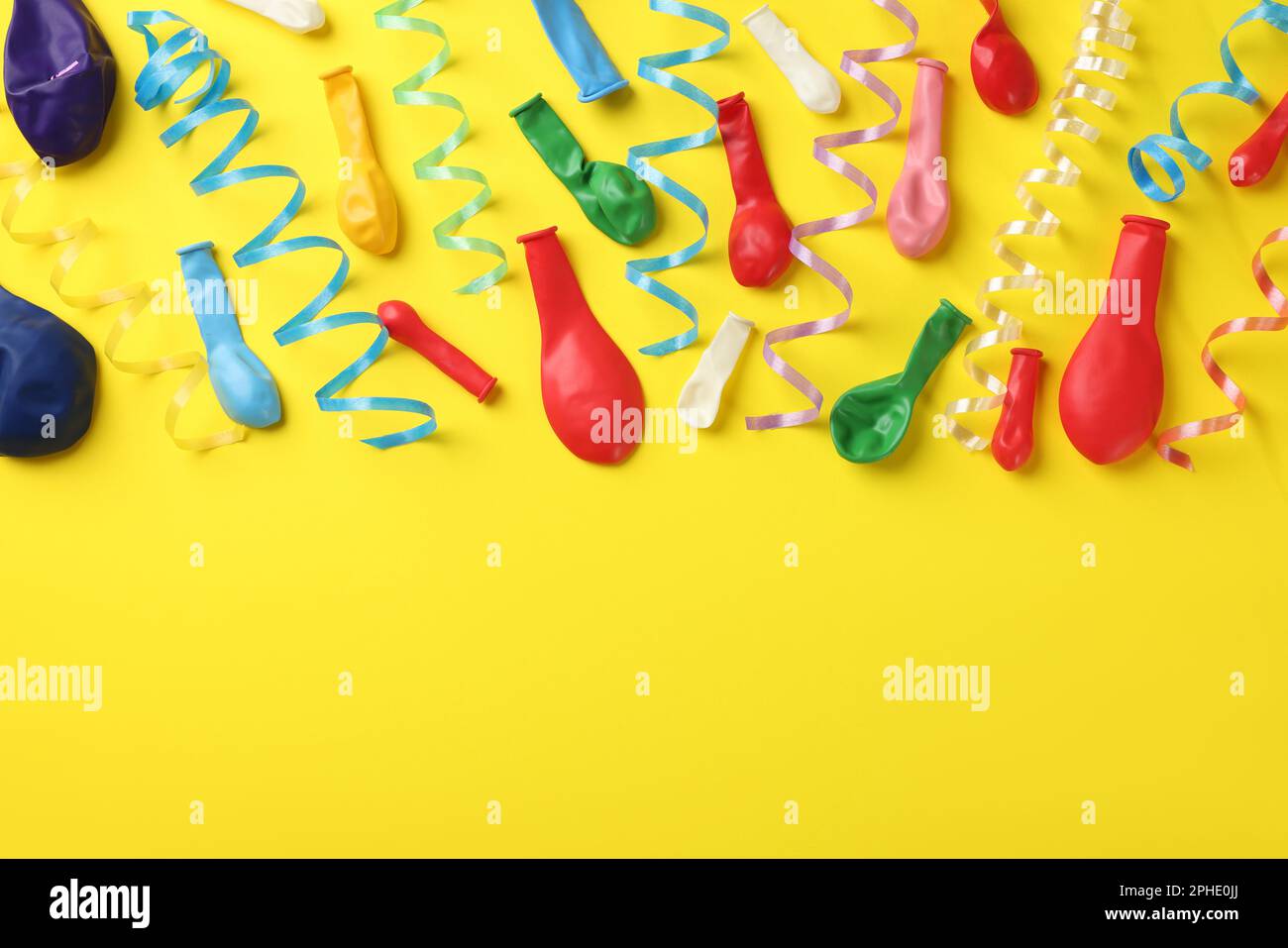 Colorful serpentine streamers and balloons on yellow background, flat ...