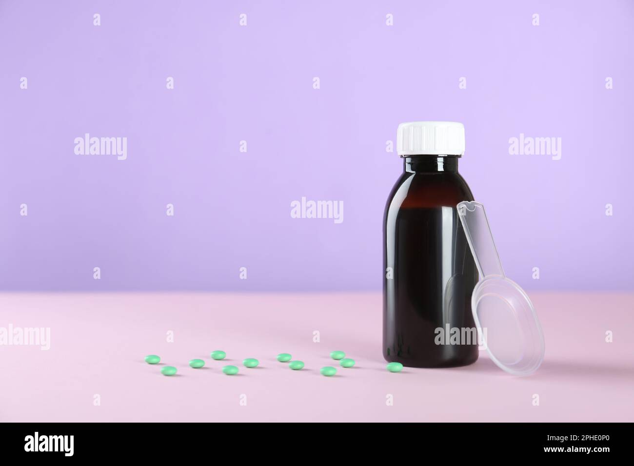 Bottle of cough syrup, dosing spoon and pills on color background ...