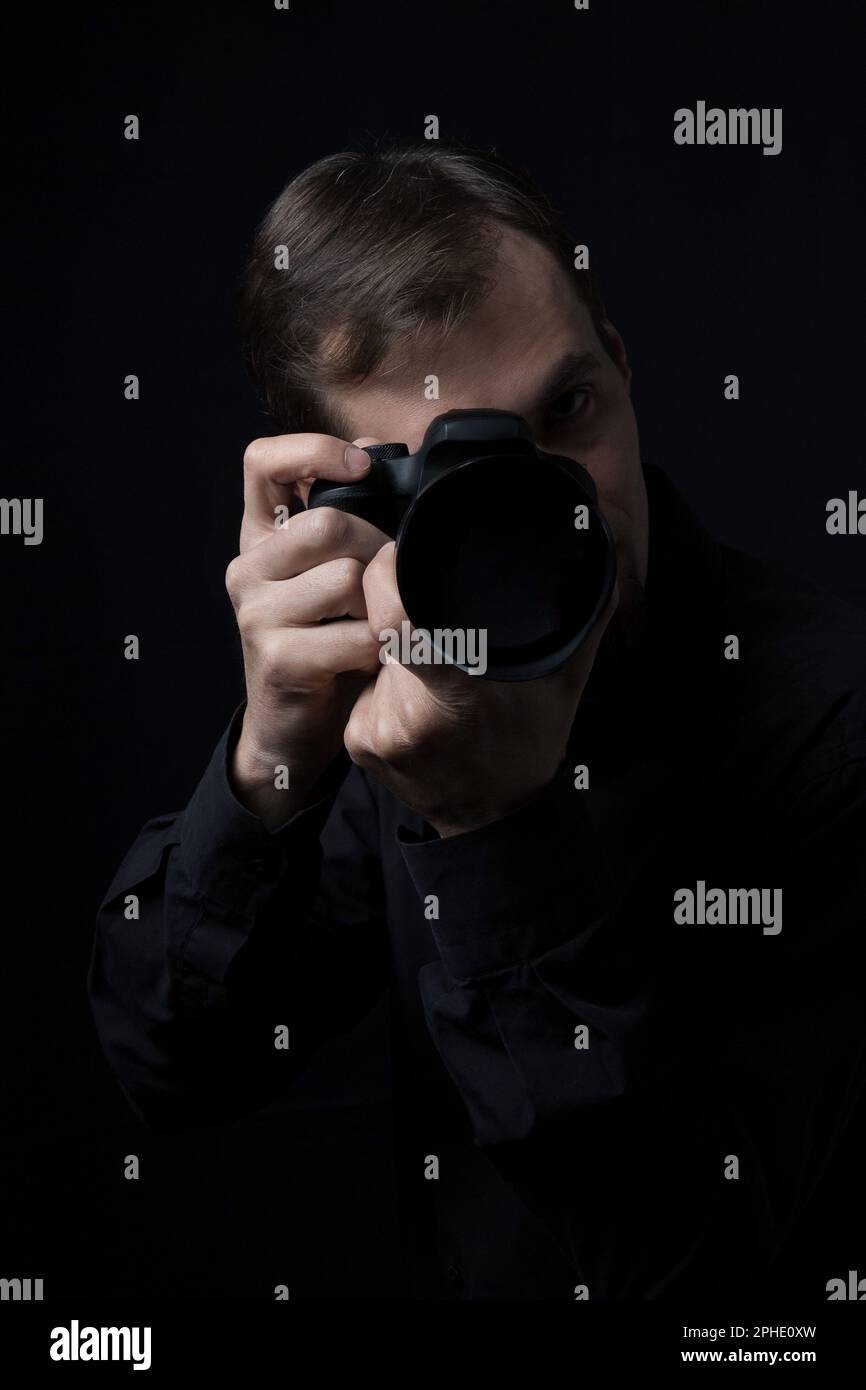 Low key portrait of a professional photographer man with a camera in ...