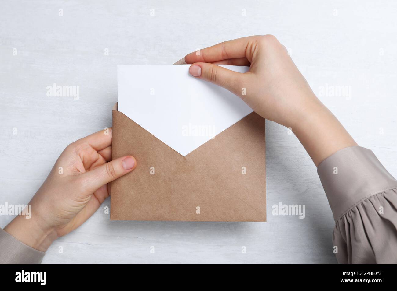 Woman taking card out of envelope at light table, top view Stock Photo ...