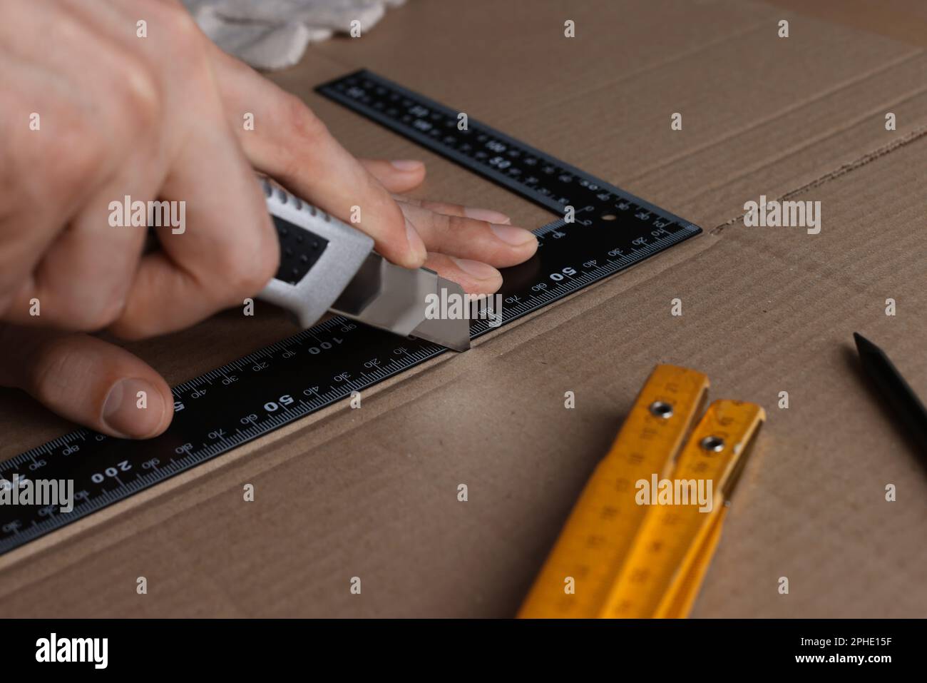 Man cutting cardboard with utility knife and ruler, closeup Stock Photo ...