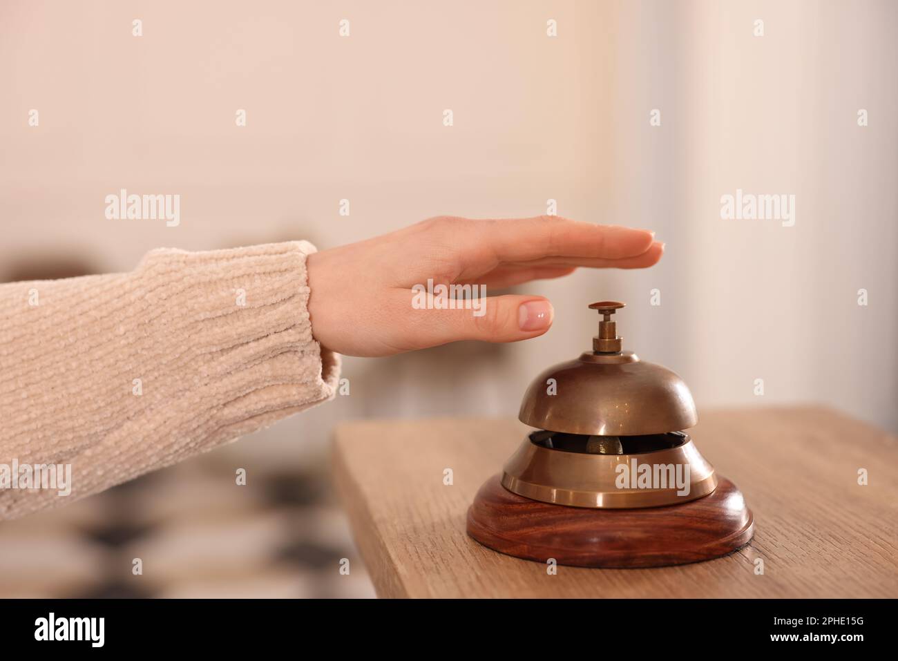 Woman ringing hotel service bell at wooden reception desk, closeup ...