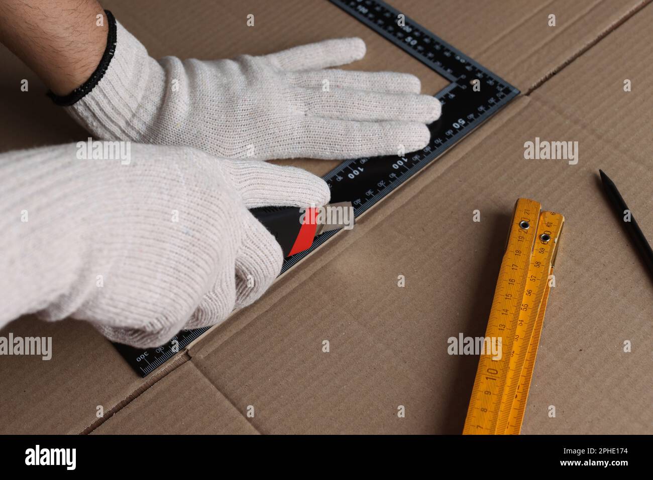 Worker cutting cardboard with utility knife and ruler, closeup Stock ...