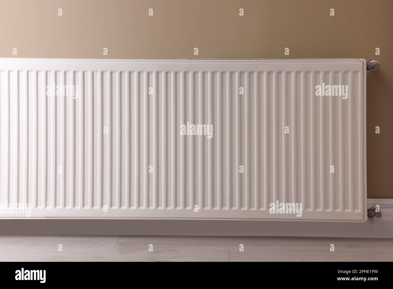 Modern radiator on beige wall. Central heating system Stock Photo - Alamy