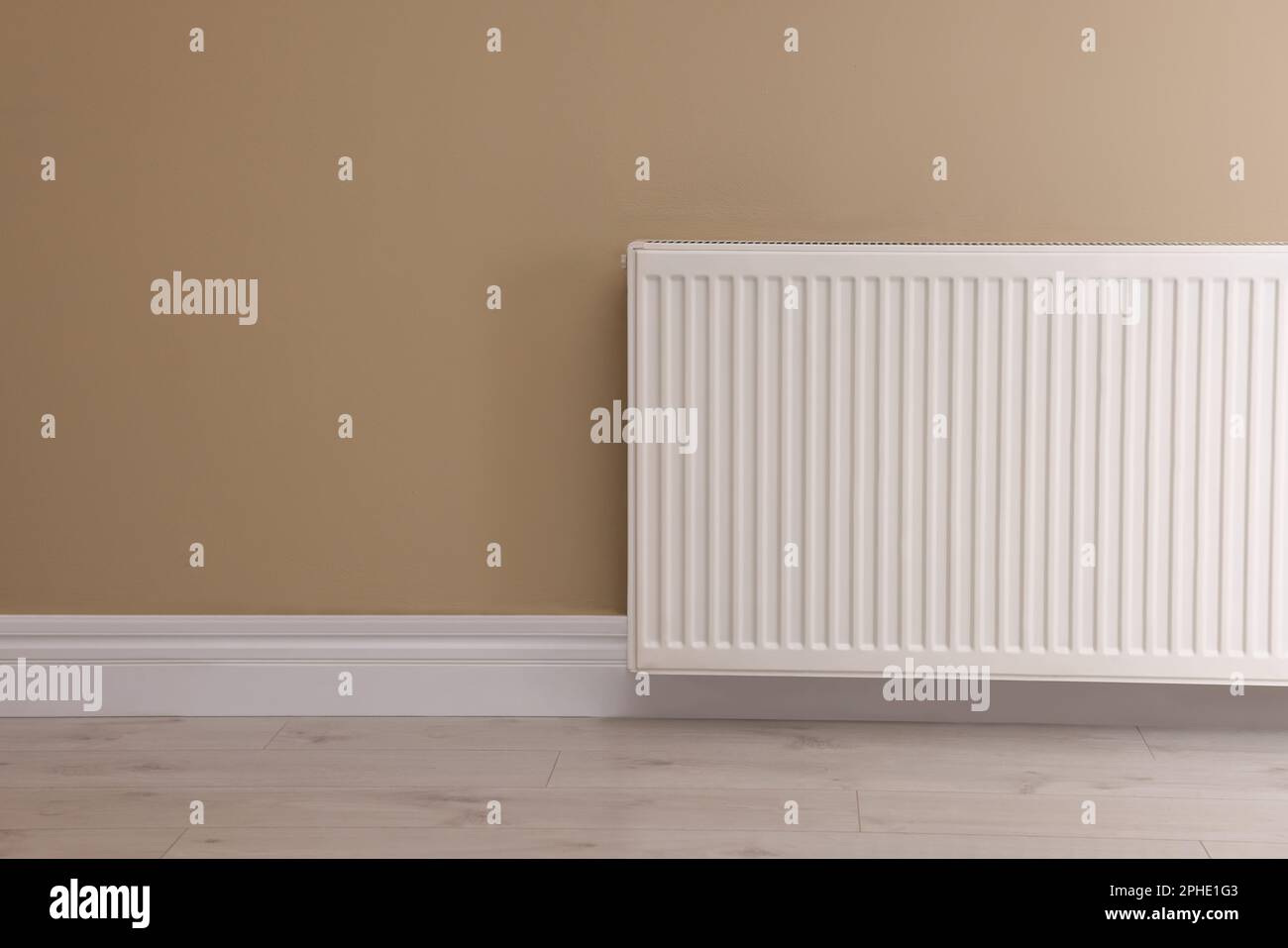 Modern radiator on beige wall, space for text. Central heating system ...