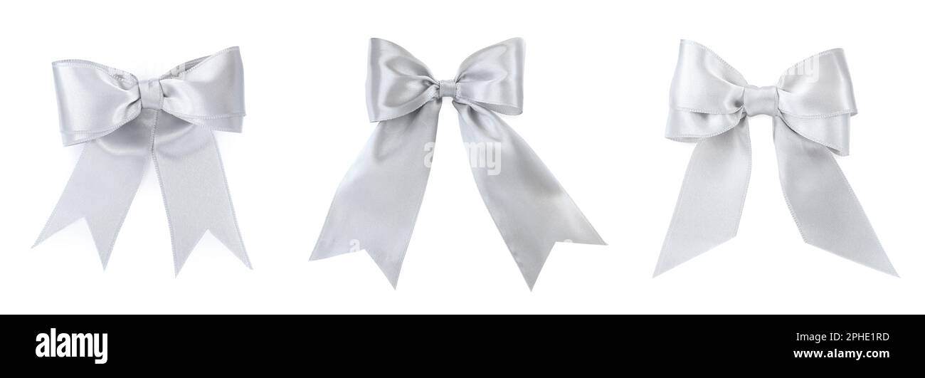 Set with beautiful silver ribbons tied in bows on white background ...