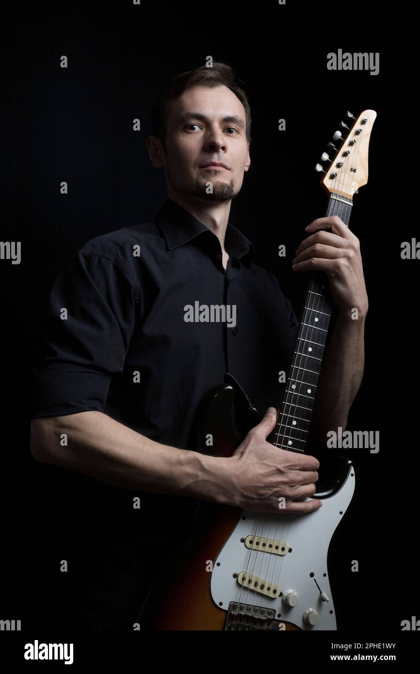 Studio low key portrait of guitarist with electric guitar with classic ...