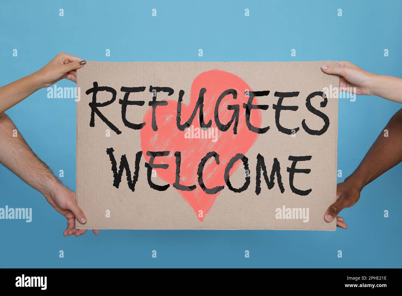 People holding sign with phrase WELCOME REFUGEES on light blue ...