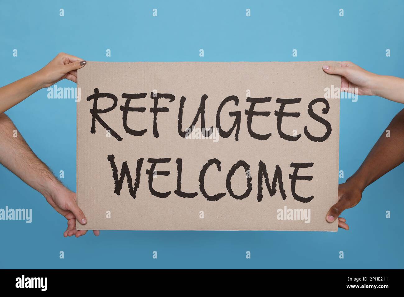 People holding sign with phrase WELCOME REFUGEES on light blue ...
