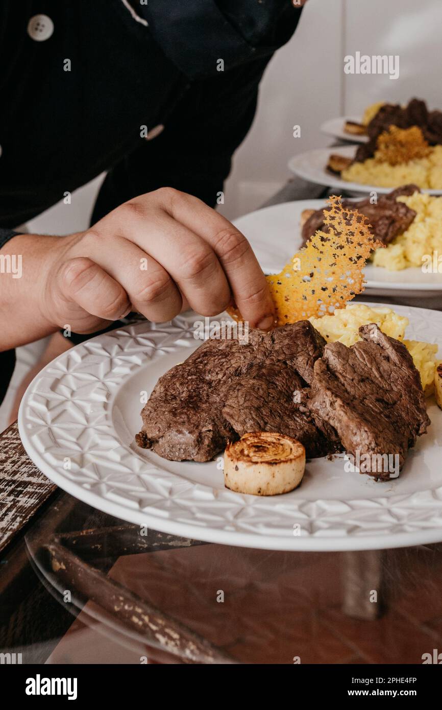 A closeup of a professional chef plating a perfectly cooked steak with ...