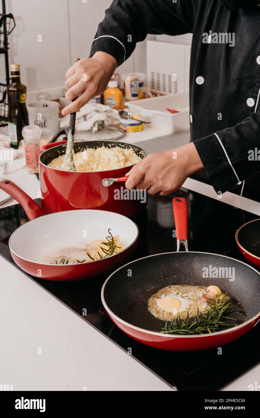 A male chef is preparing a meal in a kitchen by adding finishing ...