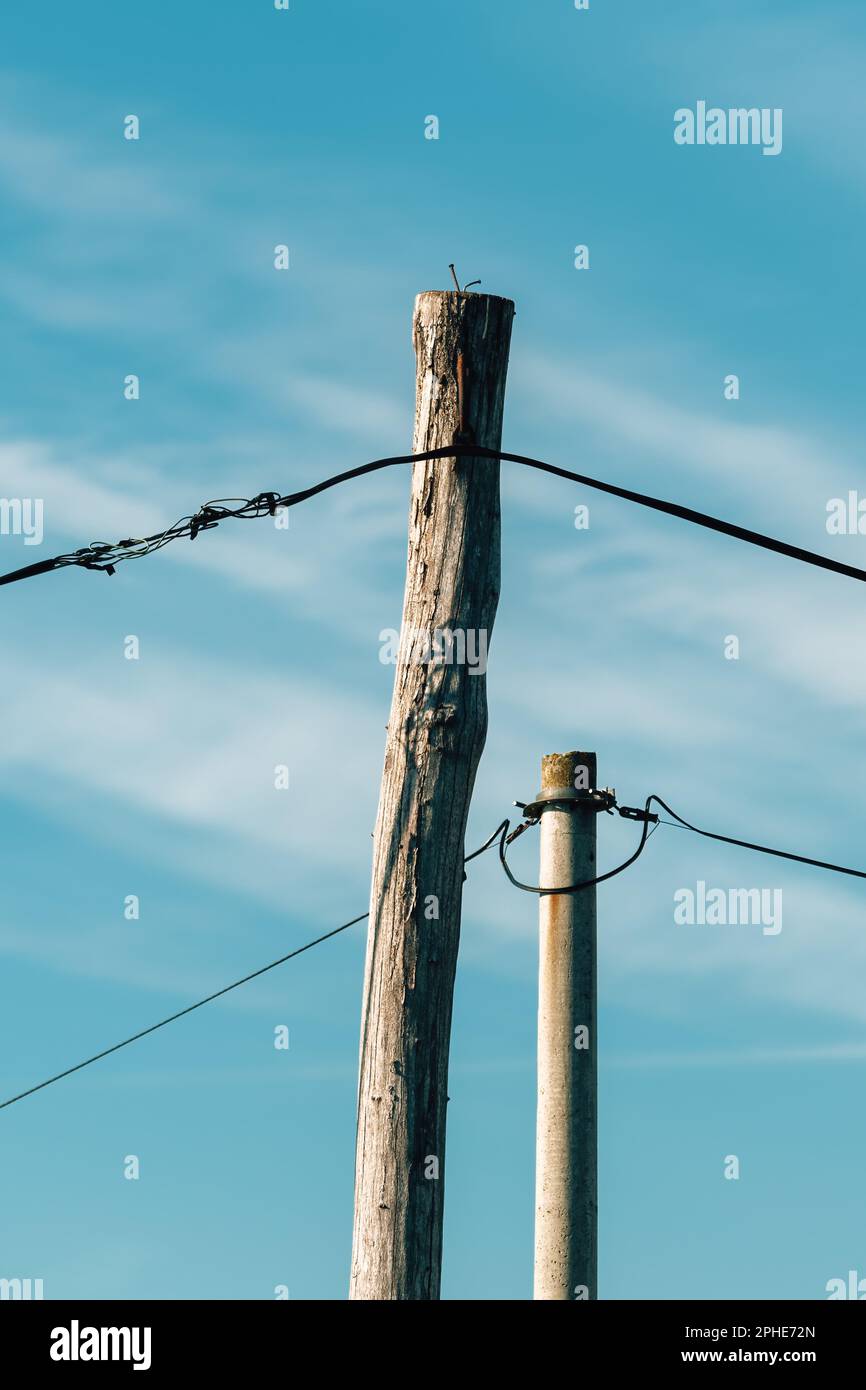 Two electricity poles, a wooden and a concrete one with electrical ...