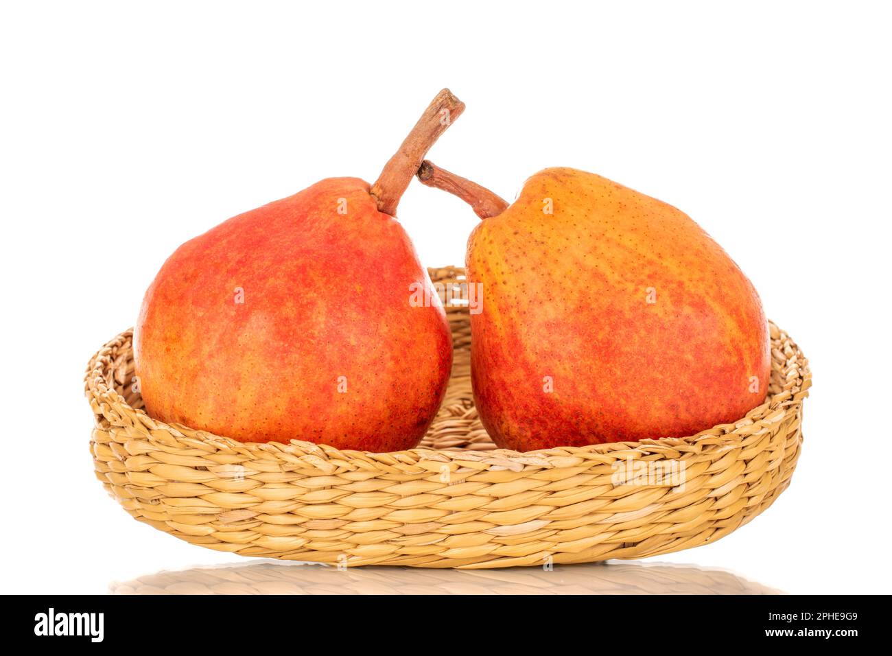 Two organic Bartlett pears in a straw bowl, macro, isolated on white ...