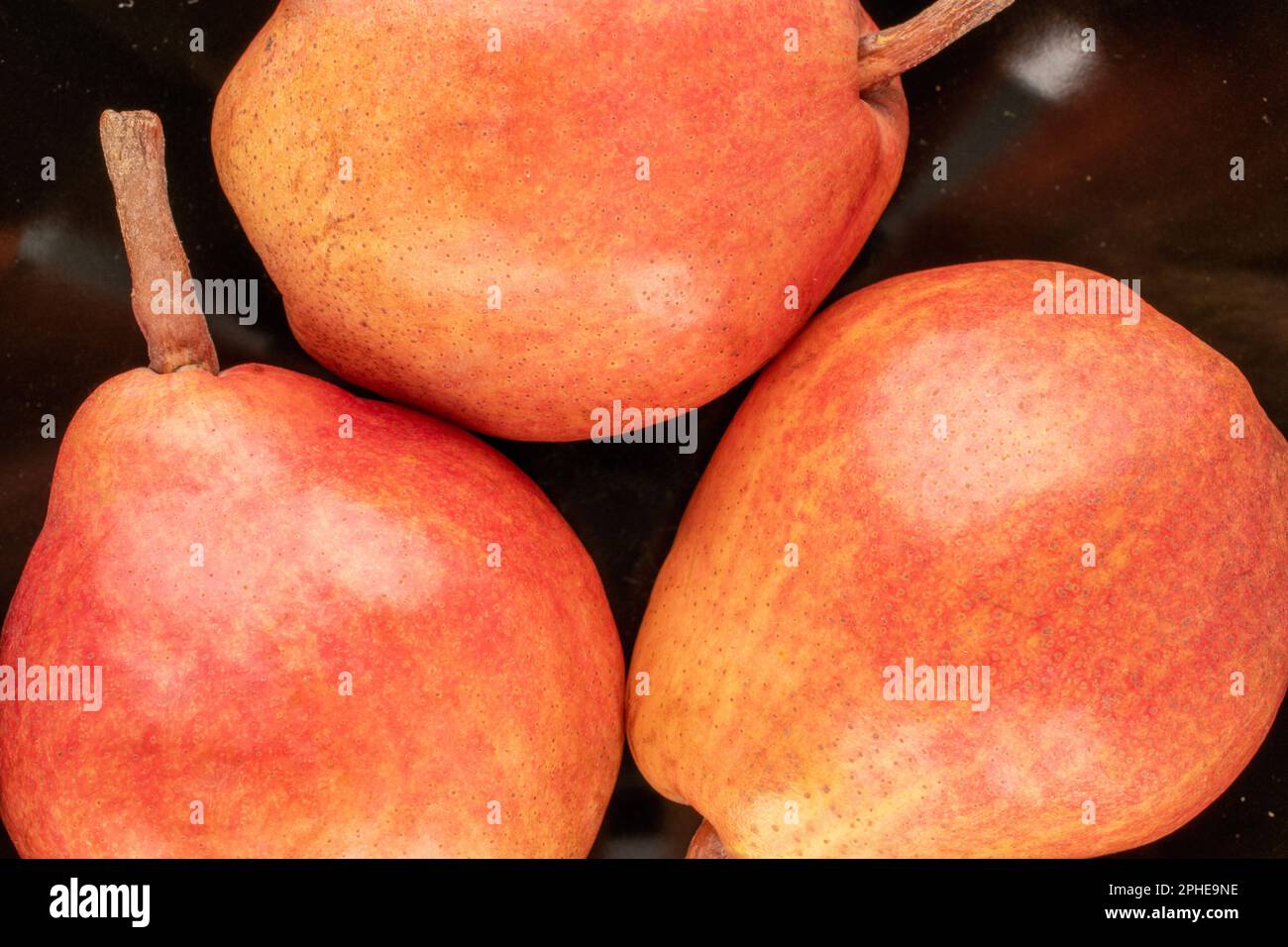Three organic Bartlett pears in a black ceramic plate, macro, top view ...