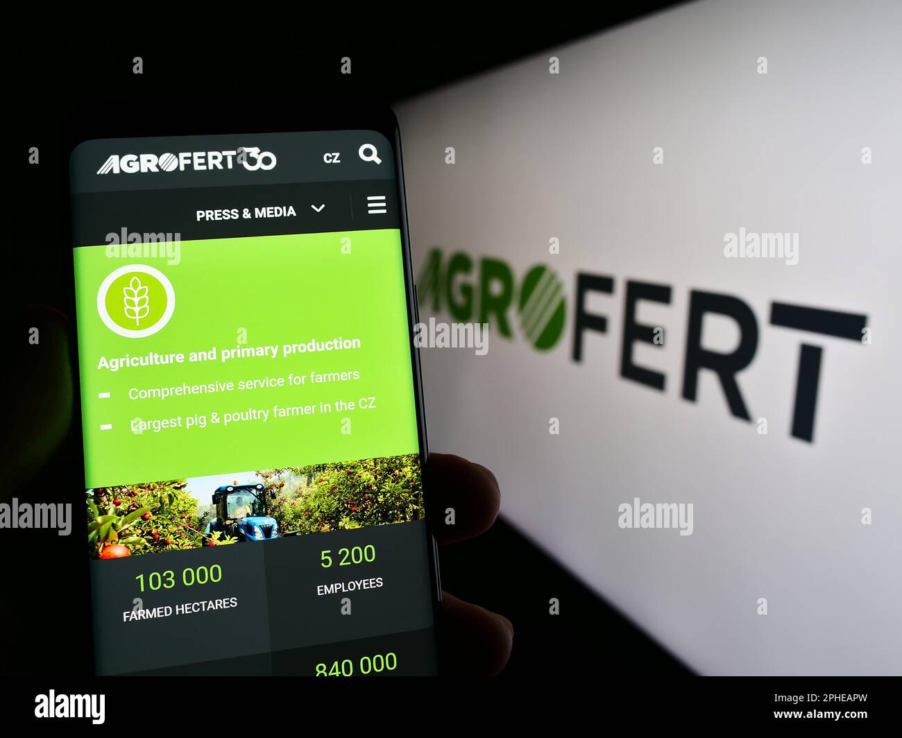Person holding cellphone with webpage of Czech company Agrofert a.s. on screen in front of ...