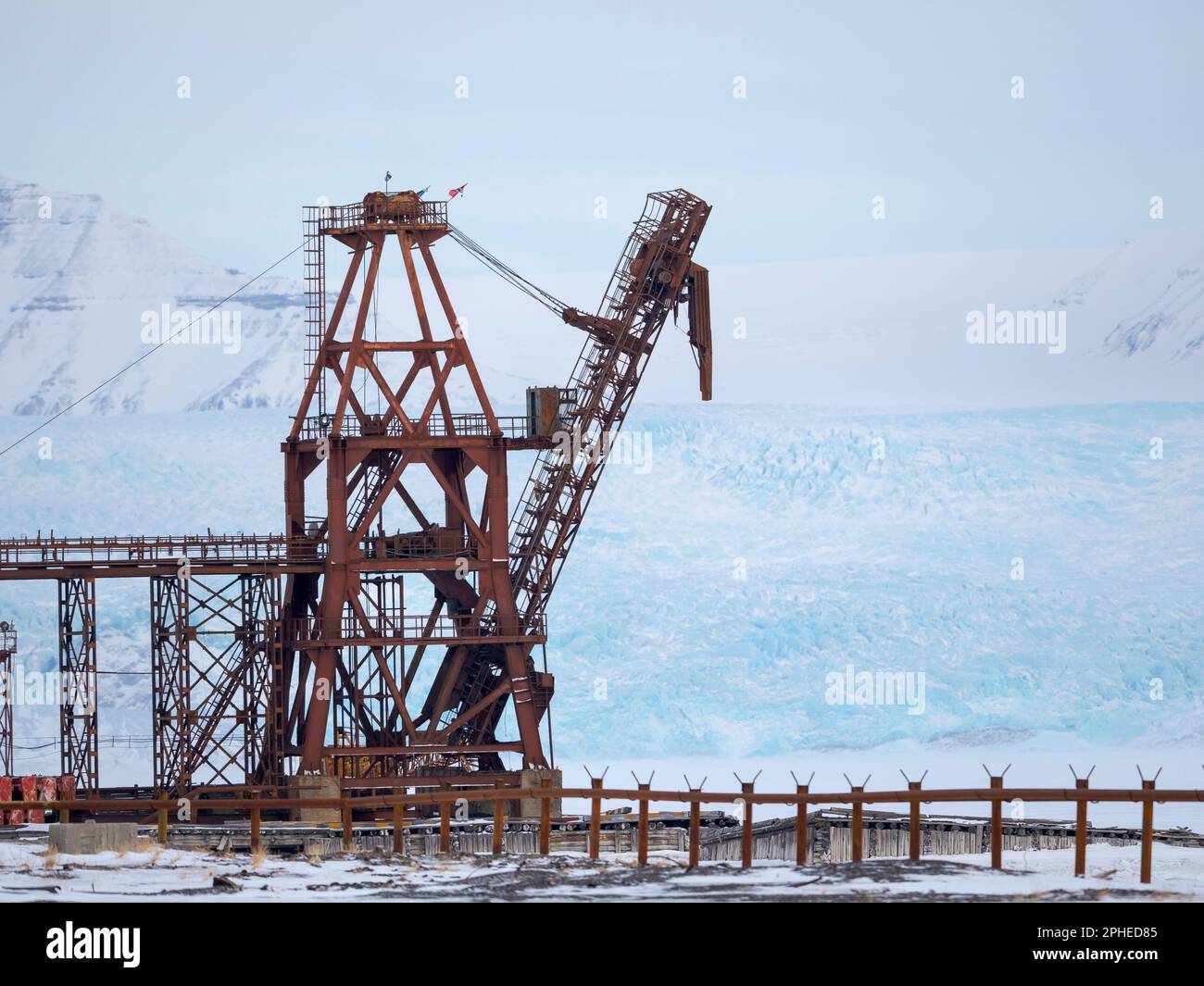 Harbour with loading crane, glacier Nordensjoeldbreen in the background ...