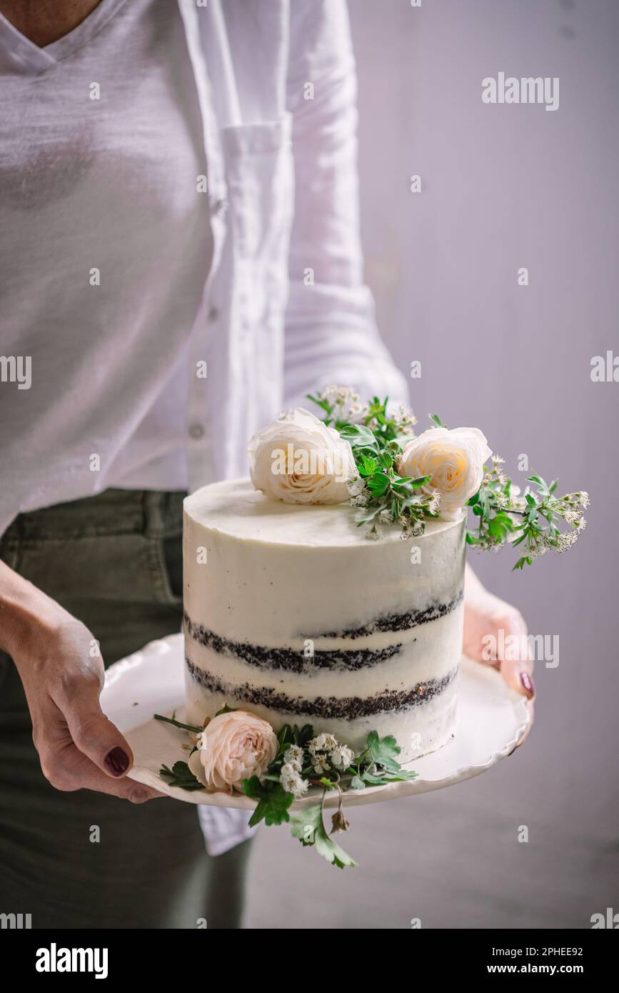 Unrecognizable female demonstrating appetizing cake decorated with ...