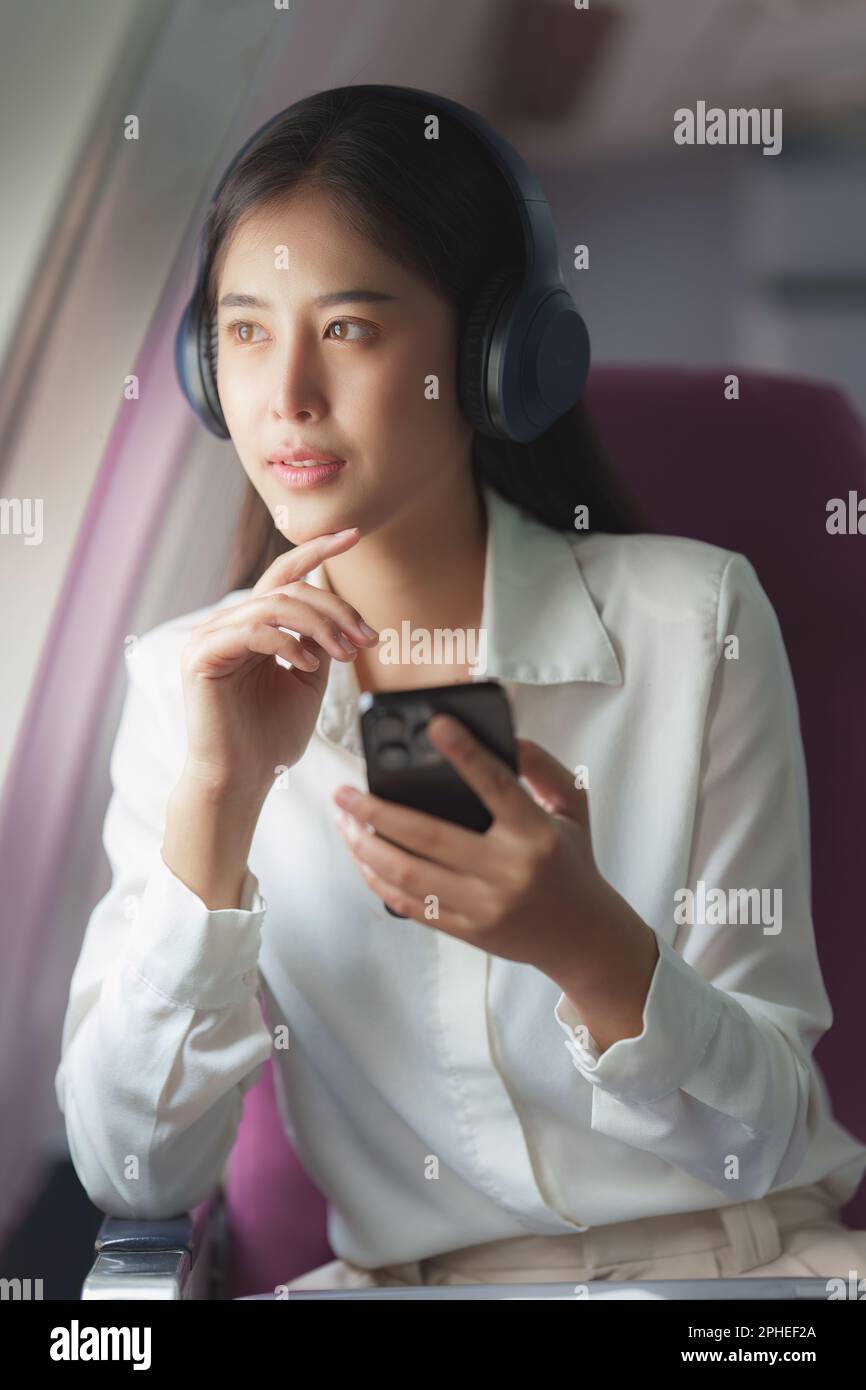 Beautiful Asian business woman listen music by mobile phone during ...