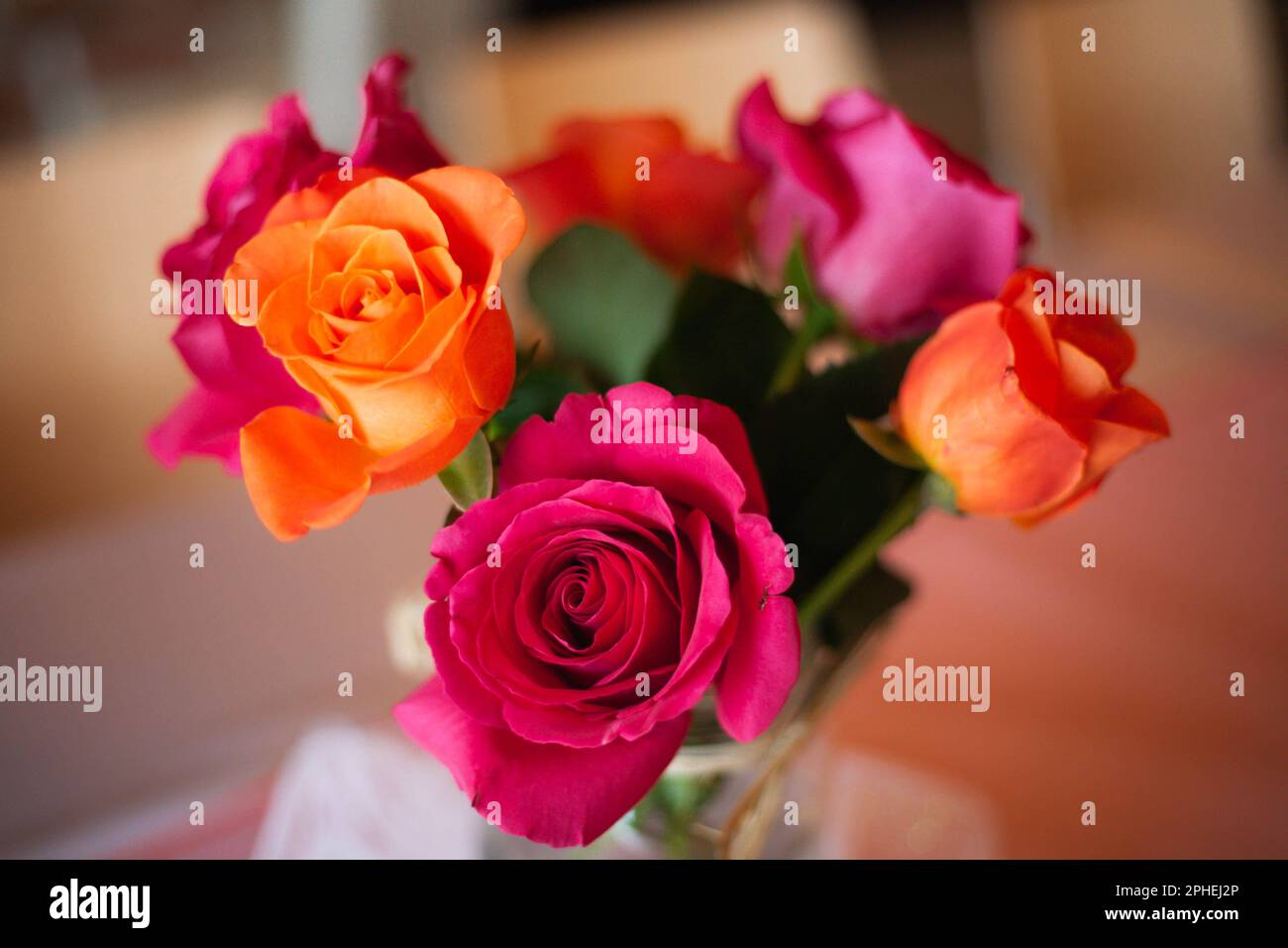 A clear glass vase filled with an assortment of brightly colored roses ...