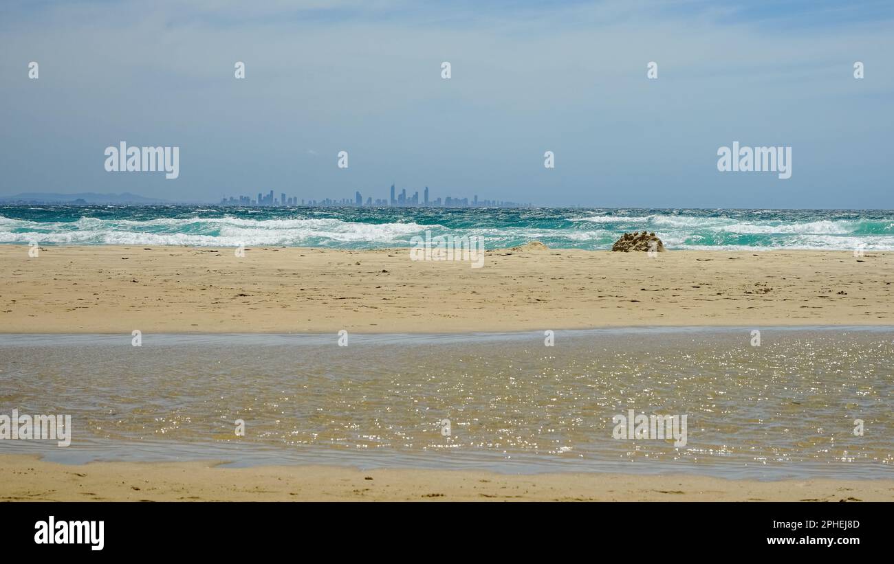 View across shallow tidal pool on the beach to the ocean surf, to the ...