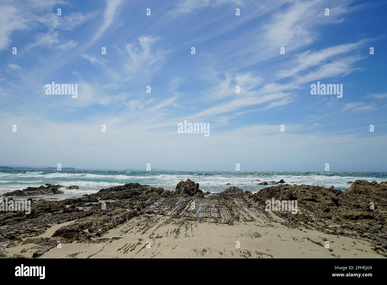 View over rock formation on the beach and surf to the horizon, beneath ...