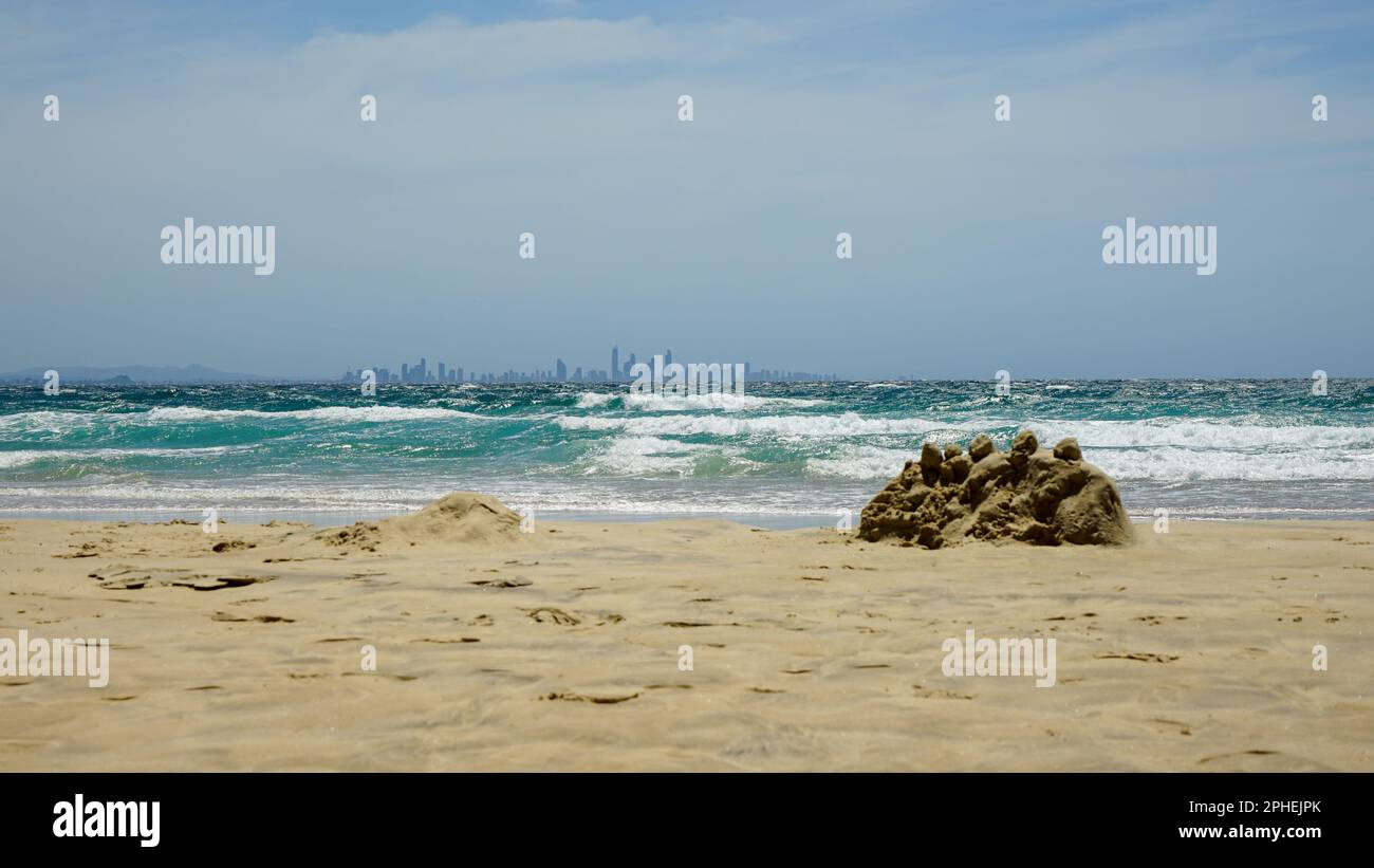 View past a sandcastle on the beach to turbulent surf, and high rise ...