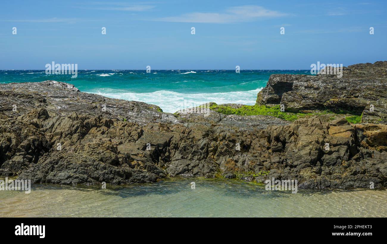 View over a shallow sand-bottomed pool to rock, and ocean stretching to ...