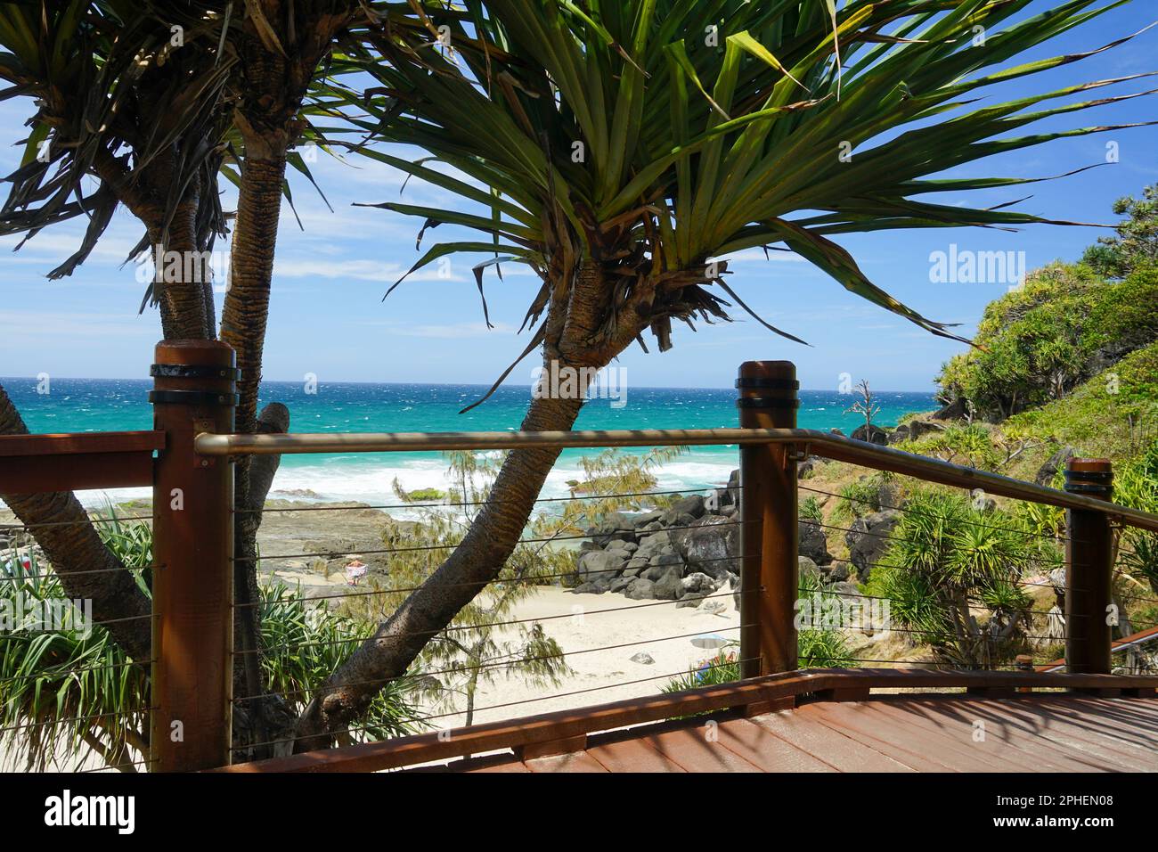 Seascape with fence and pandanus palm in the foreground, sand, rocks ...