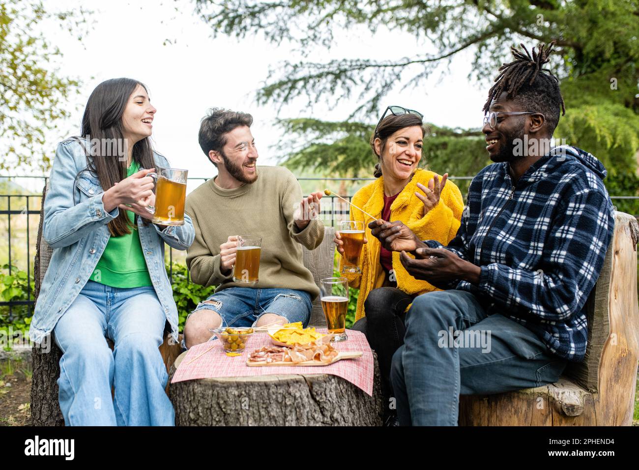 Friends drinking beer and eating snack outside at pub, diverse people ...