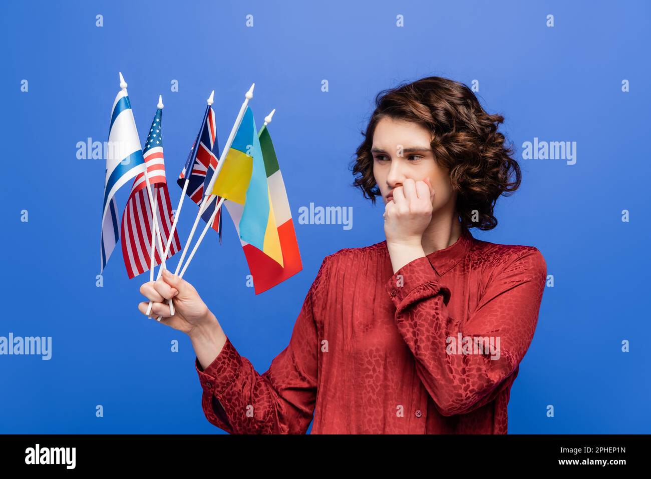 thoughtful woman holding hand near face while looking at flags of ...