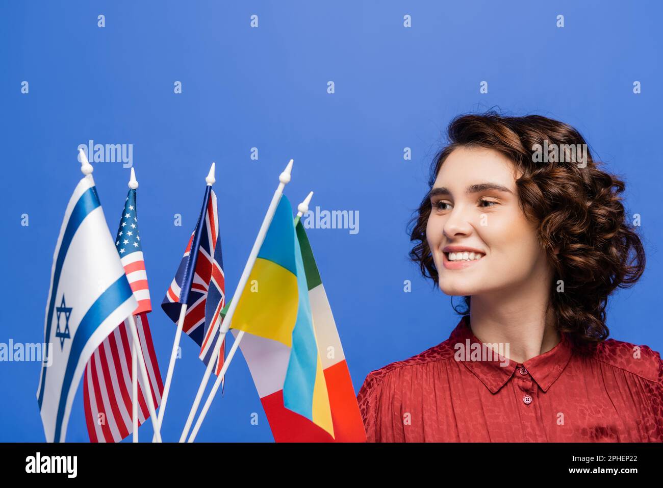 pleased young woman looking at flags of various countries isolated on ...