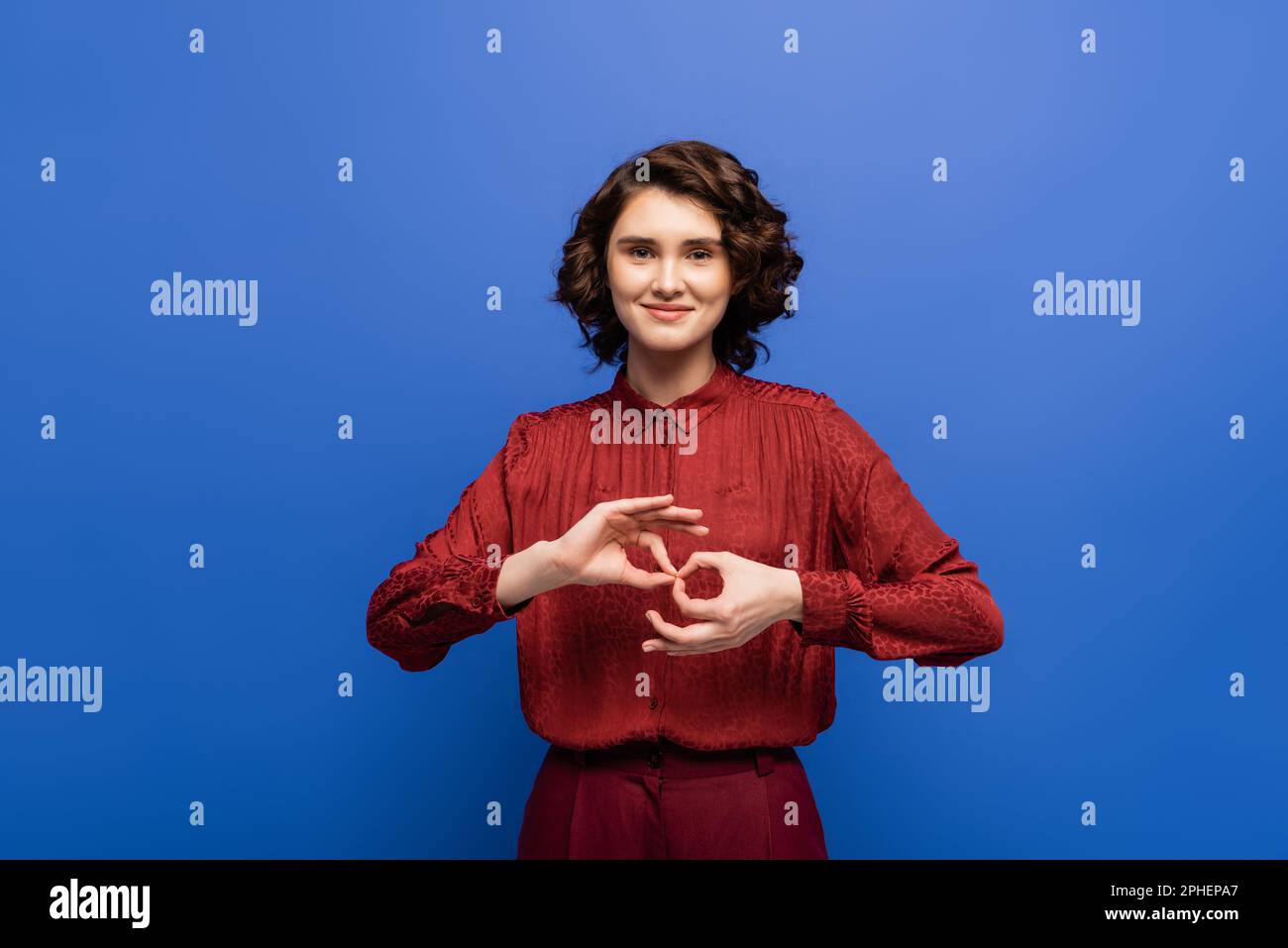 young and cheerful woman looking at camera and showing symbol meaning ...