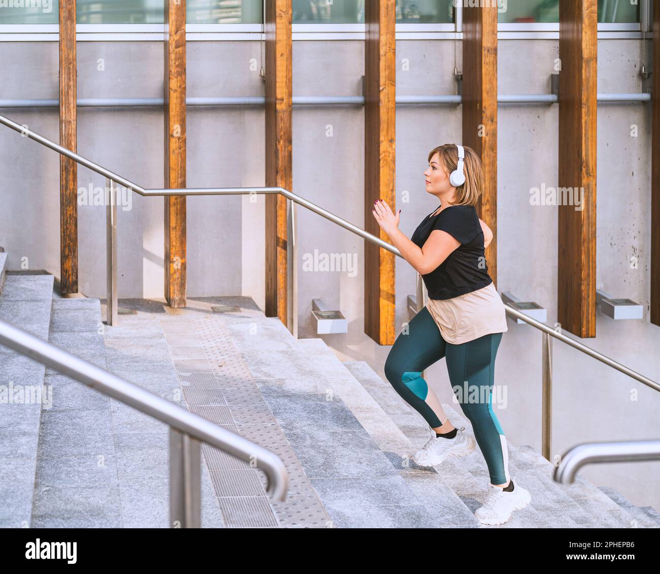 Plus size woman running on a stairway in the city, fitness and ...