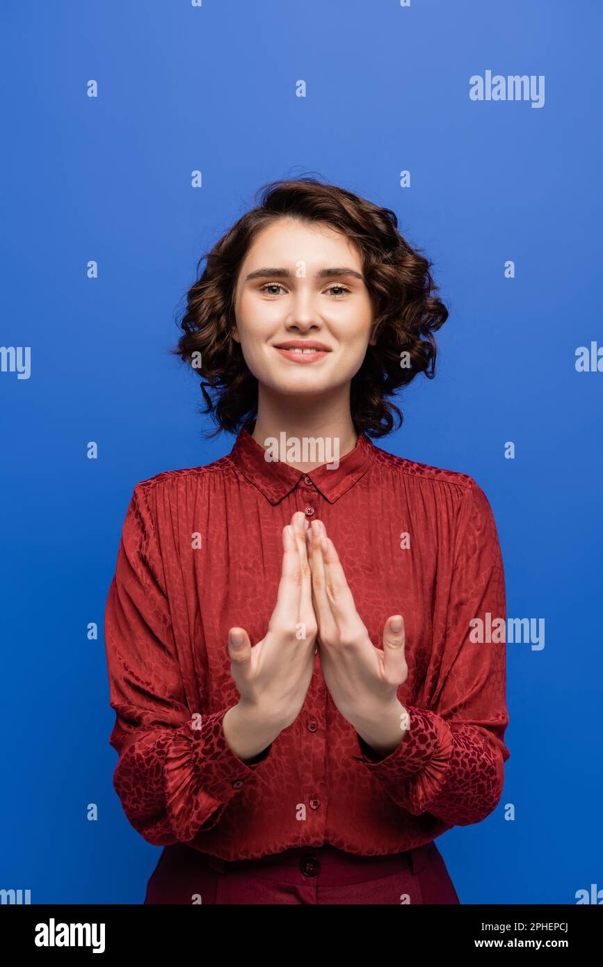 positive teacher smiling at camera and showing gesture meaning happy on ...