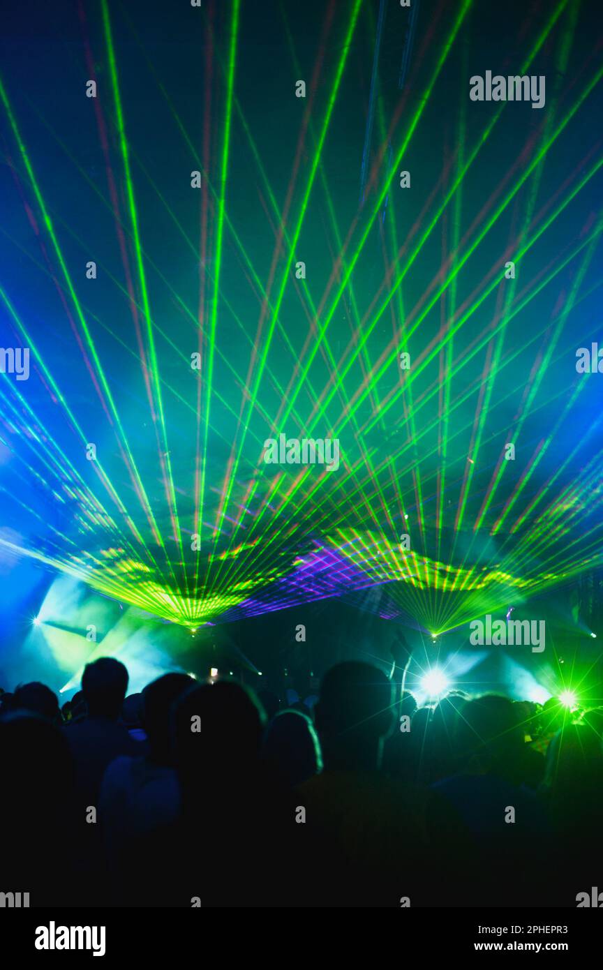 From below shot of bright beams of green laser lights illuminating ...