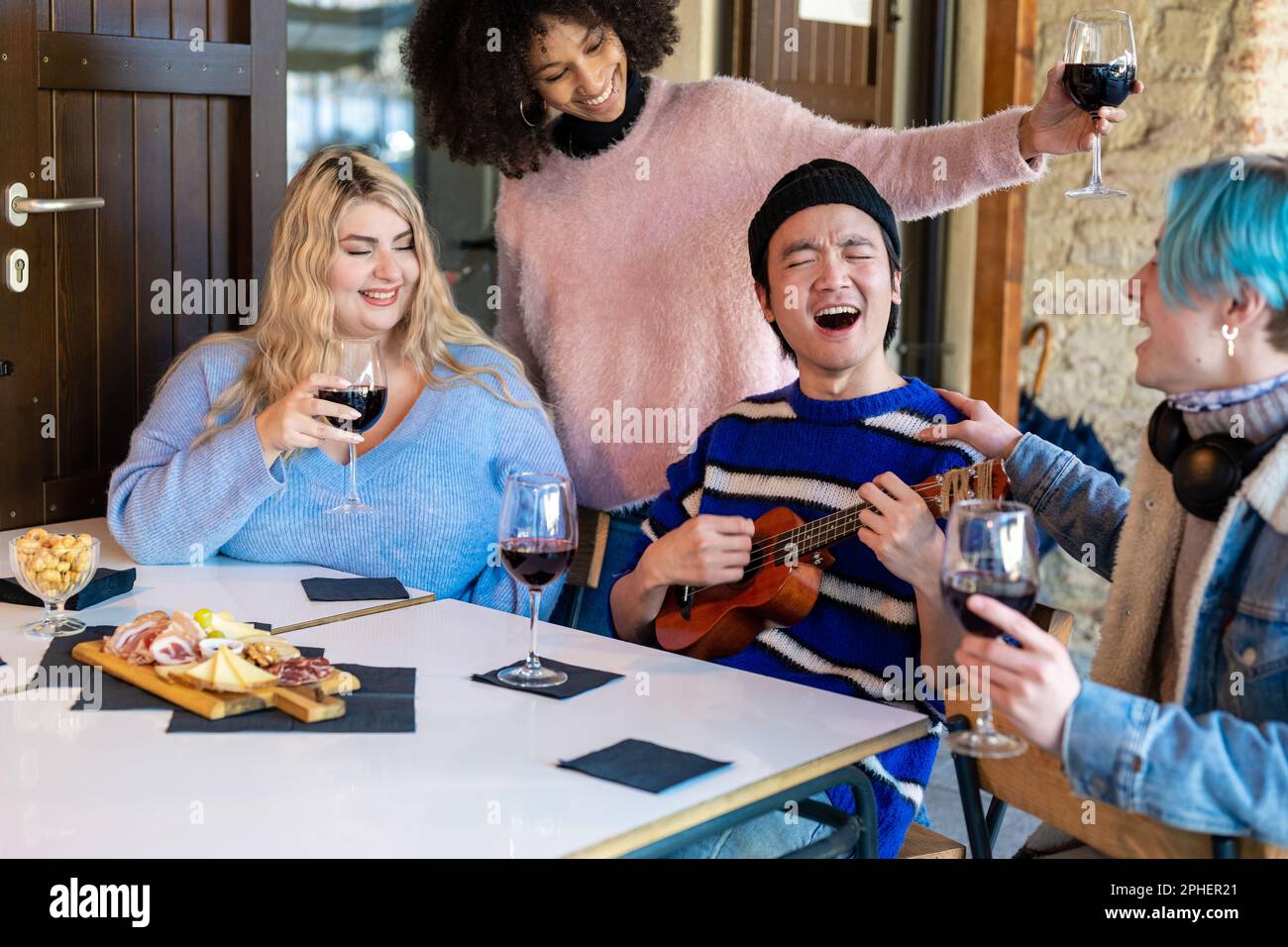 International group of friends sitting at a table in an outdoor pub ...