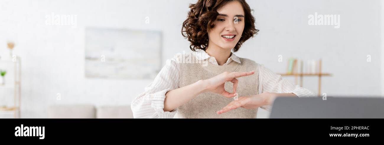 happy teacher with curly hair showing sign language gesture during ...
