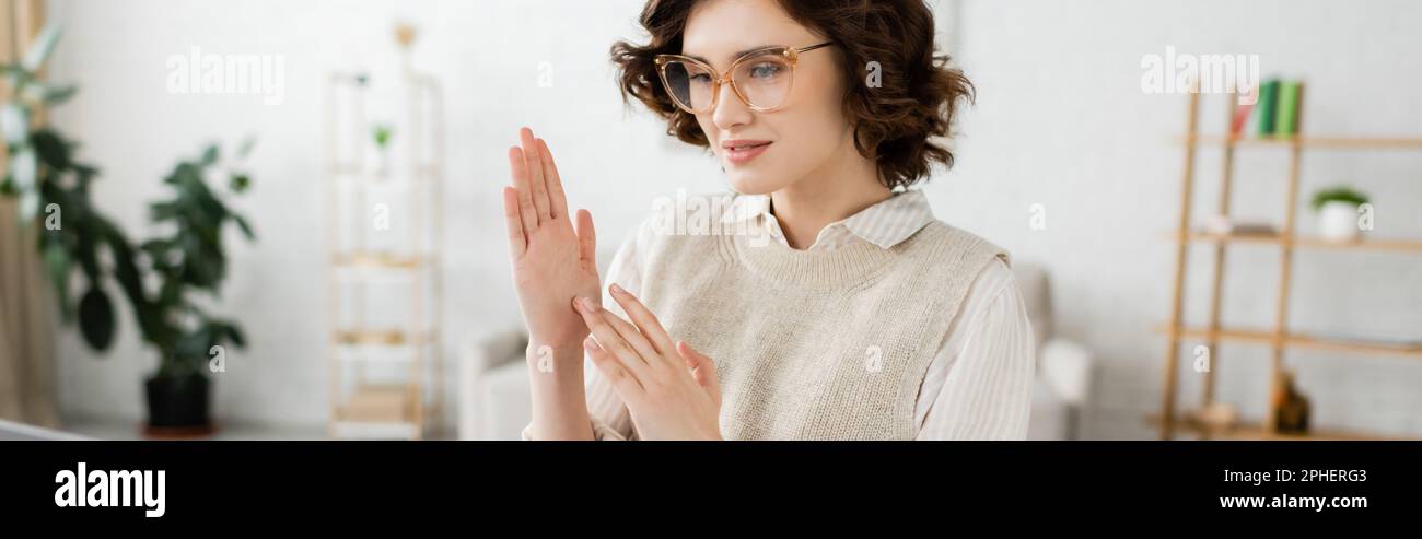young teacher with curly hair showing two handed sign language gesture ...