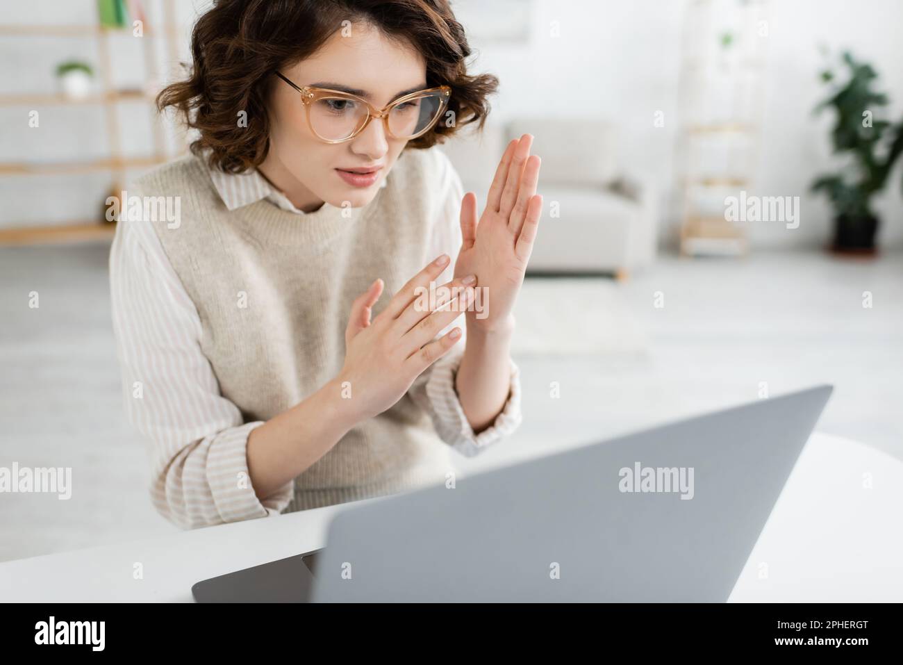 young teacher in glasses showing two handed sign language gesture while ...
