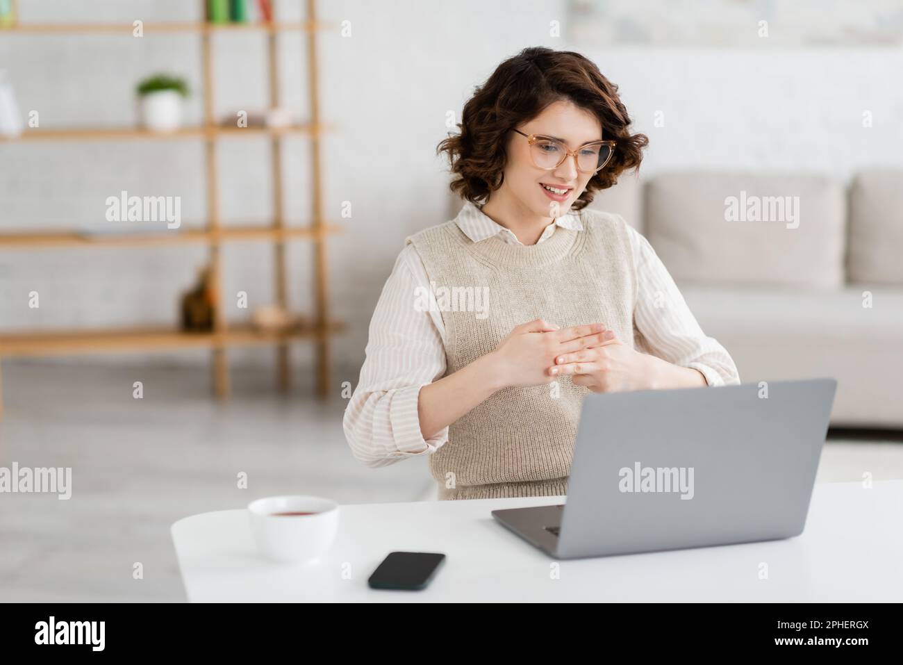 happy young woman in glasses teaching sign language during online ...
