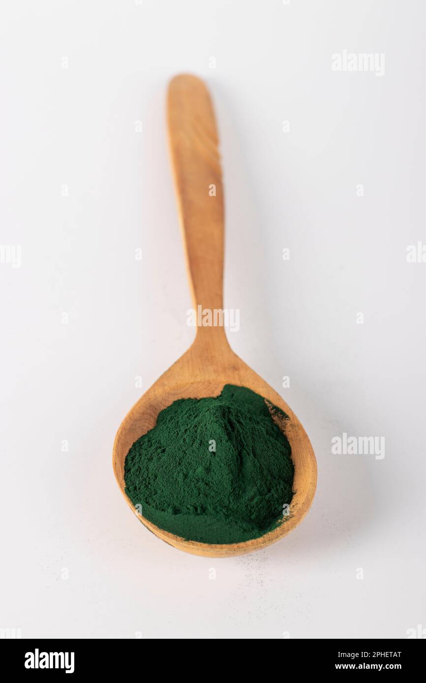 Organic spirulina algae powder in wooden spoon on white background ...
