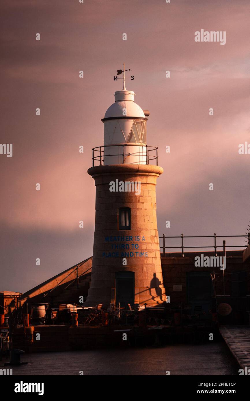 A majestic lighthouse towers at dusk with dark storm clouds Stock Photo ...