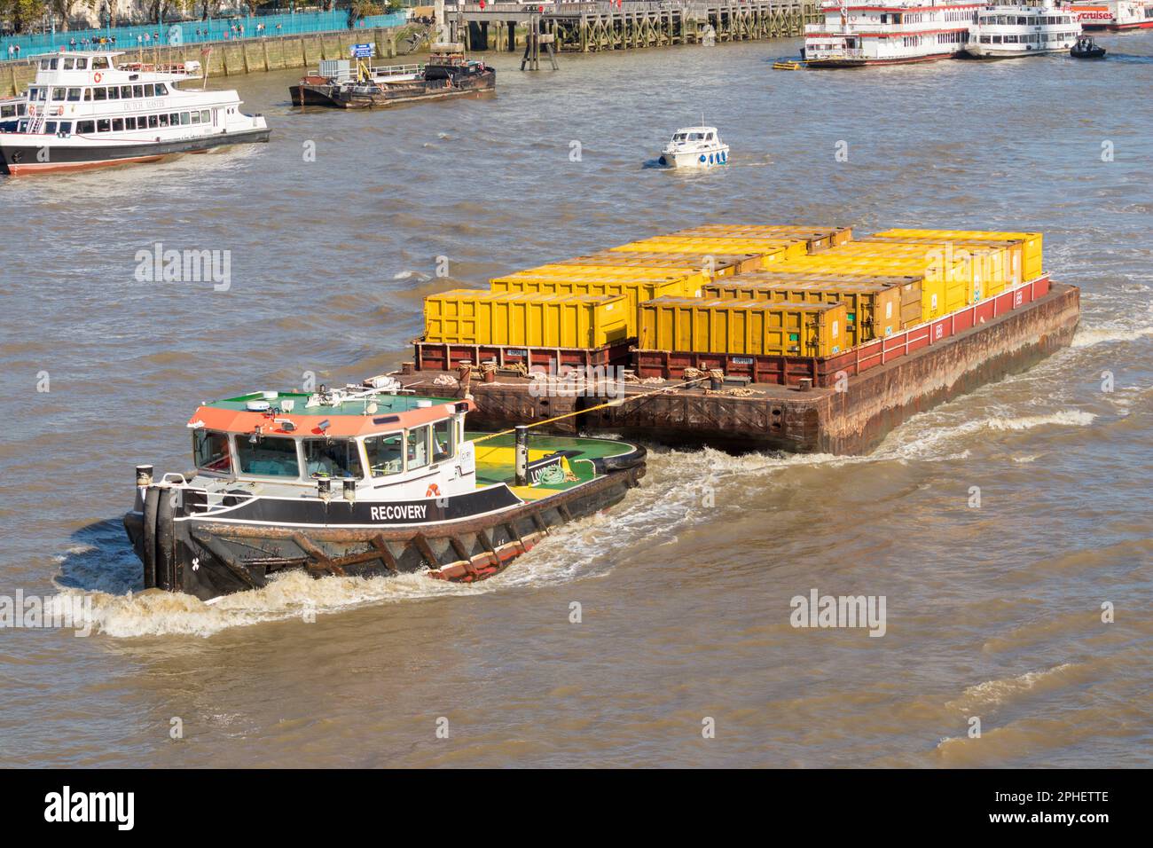 Tug boat pulling barge with yellow shipping containers along the River ...