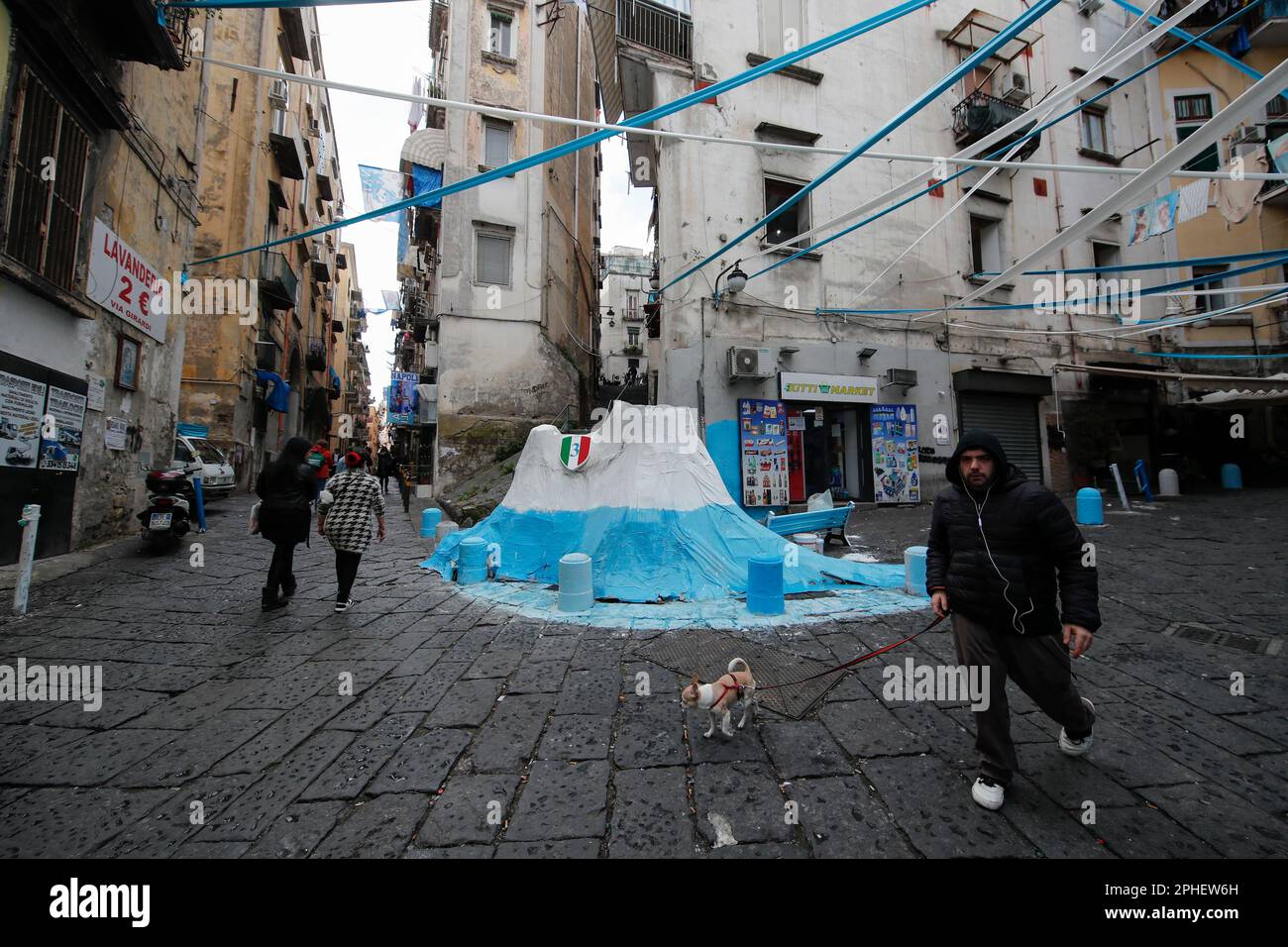 Naples, Italy. 21st Mar, 2023. A man with his dog passes next to a mock ...